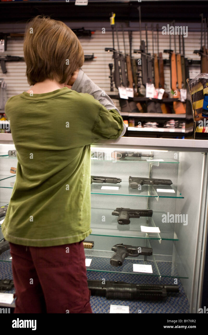 Eight year old boy looking at guns and rifles in a gun shop, United ...