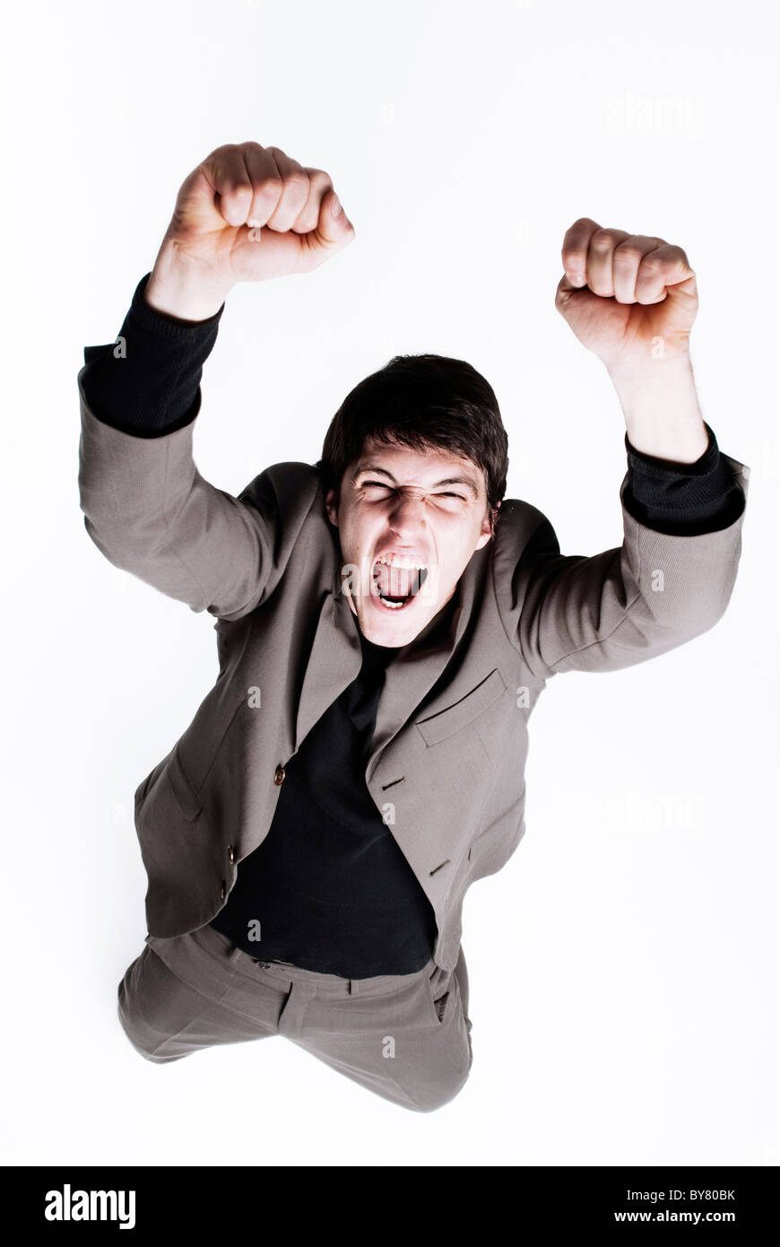 young businessman with hands up and face of victory, happy, elated ...