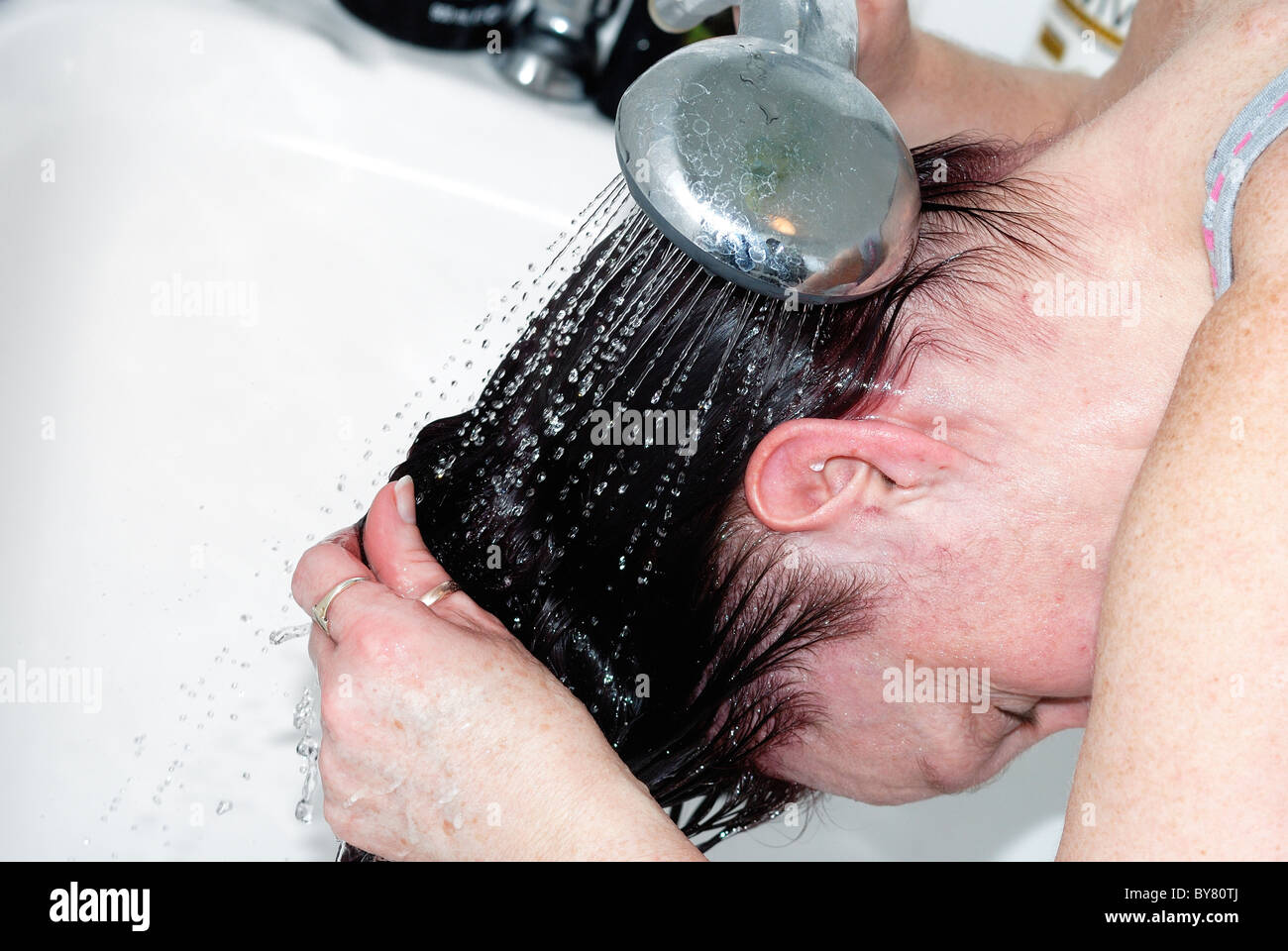 Woman rinsing hair over a bath after applying hair dye uk Stock Photo ...