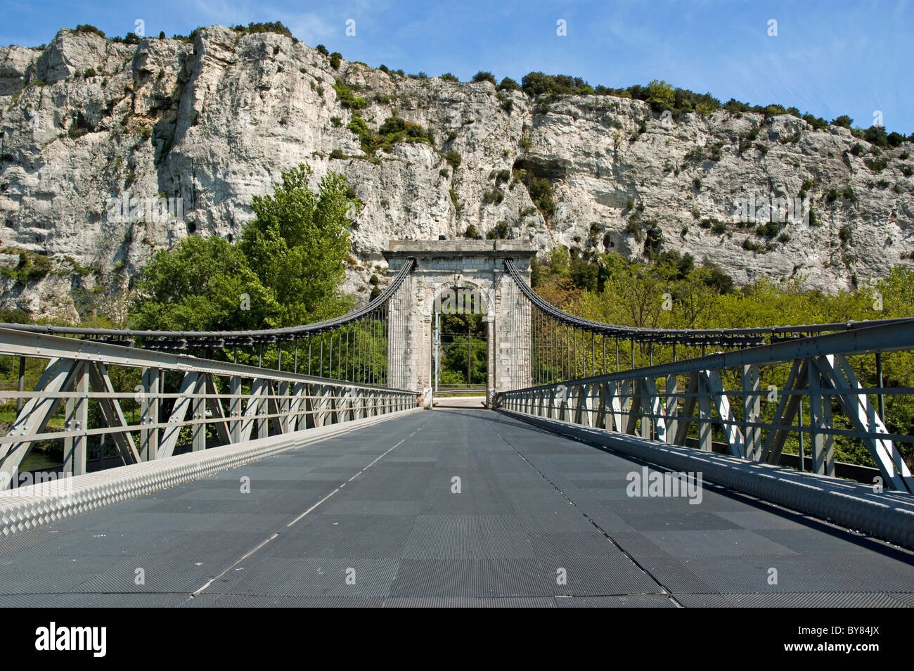 Suspended bridge over the Rhone river with cliffs in the background ...