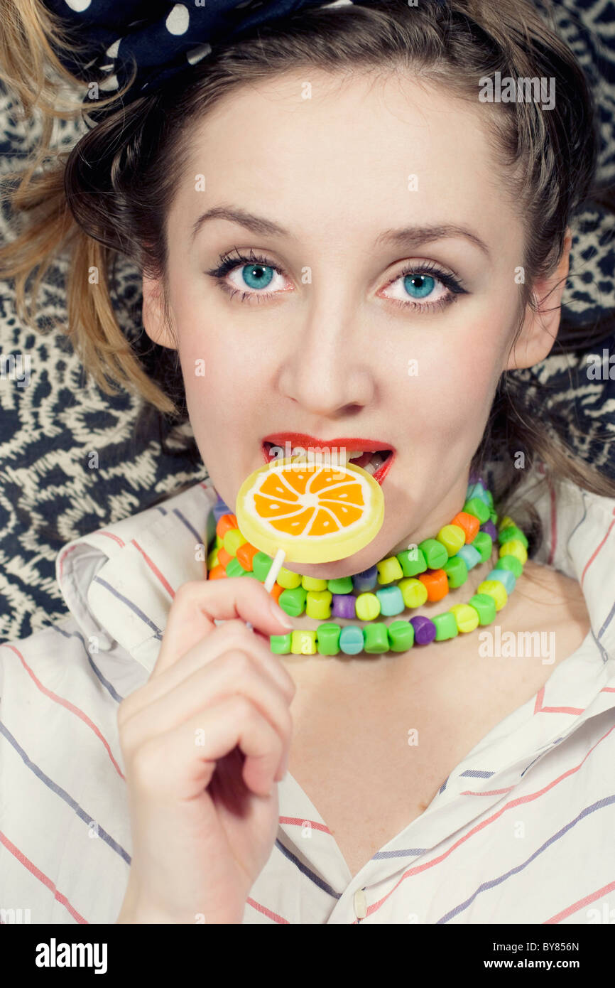 Portrait of young woman biting sugar candy Stock Photo - Alamy