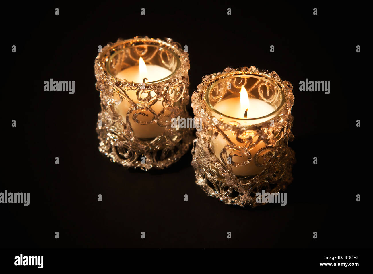 Two burning candles in glass candlesticks on black background Stock ...