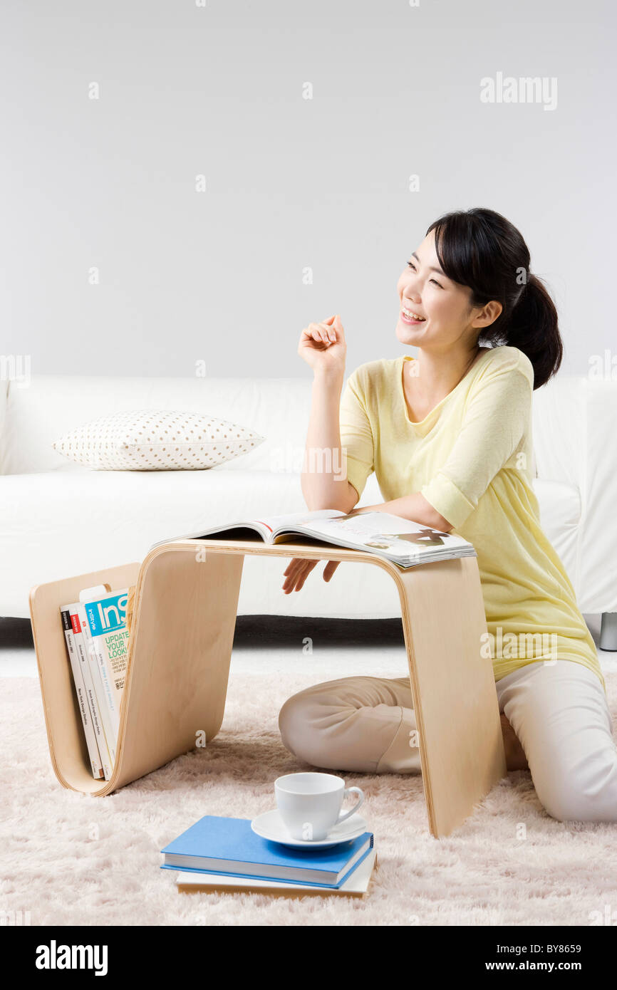 Young woman reading a magazine at table Stock Photo - Alamy