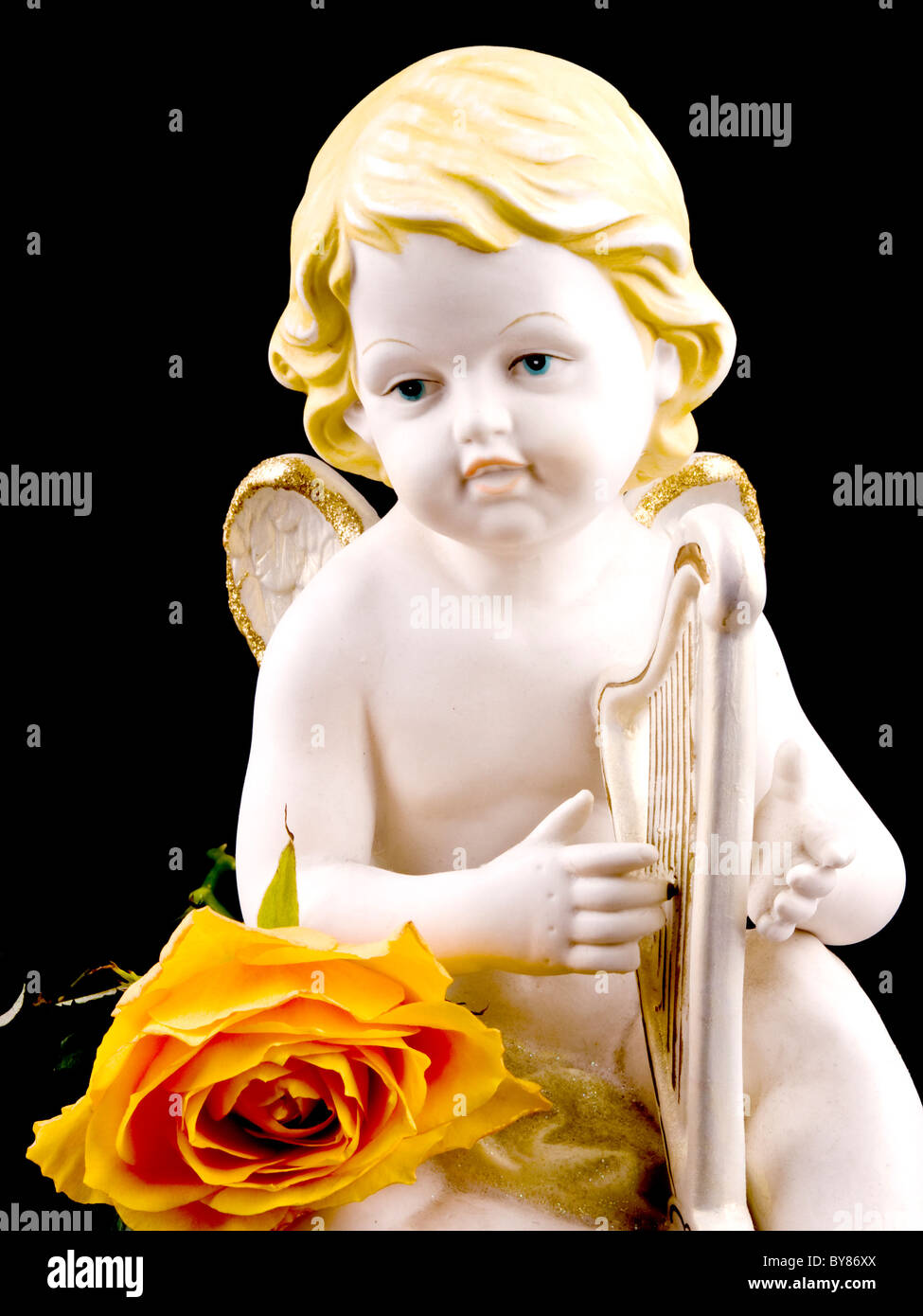 Ceramic cupid figure with tea rose on black background Stock Photo - Alamy