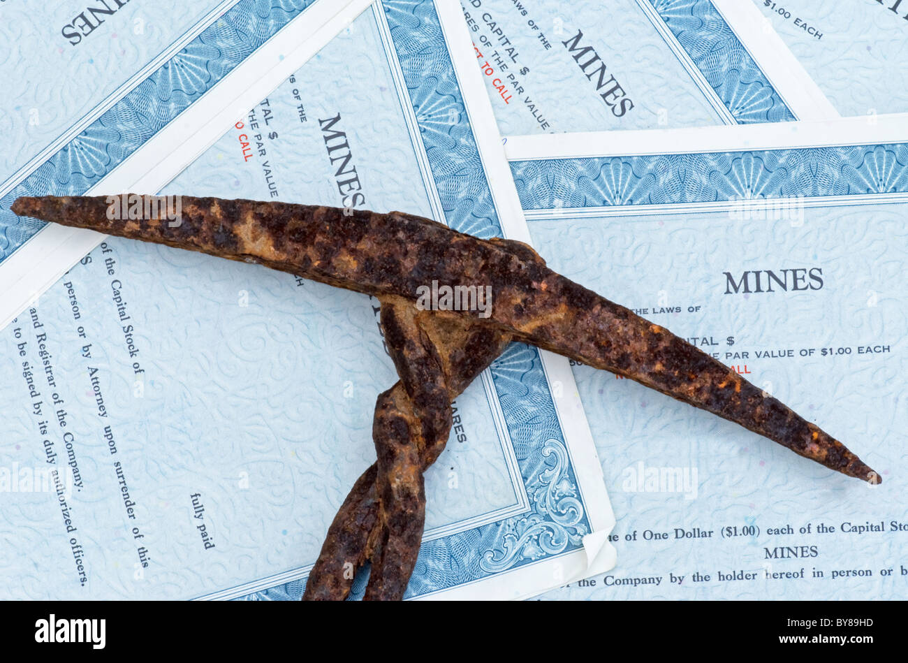 Rusty mining pick on old mine stock certificates. Old pick is weight on ...