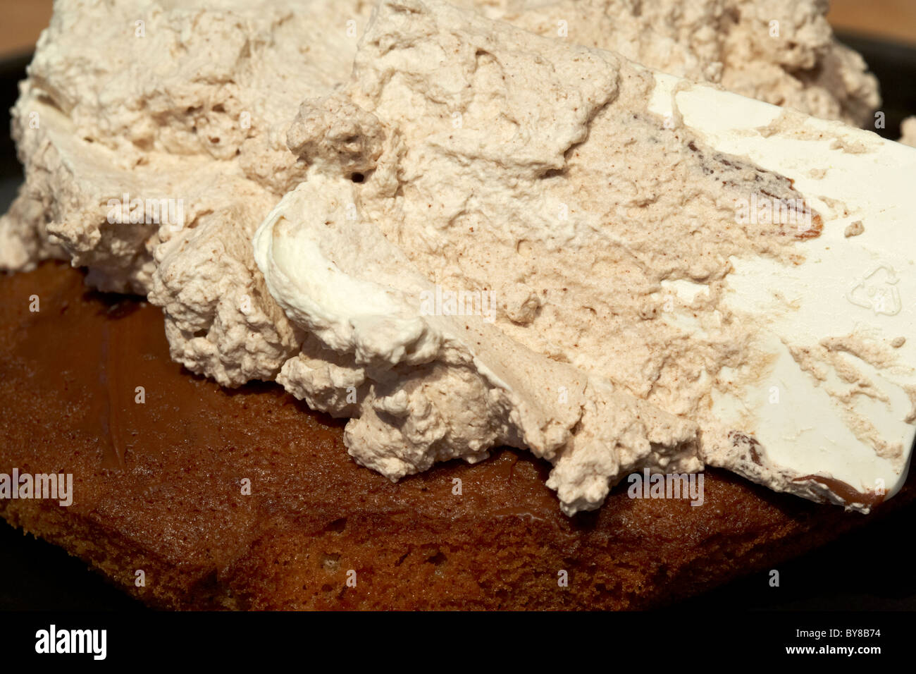 spreading fresh whipped chocolate cream spread over chocolate sponge ...