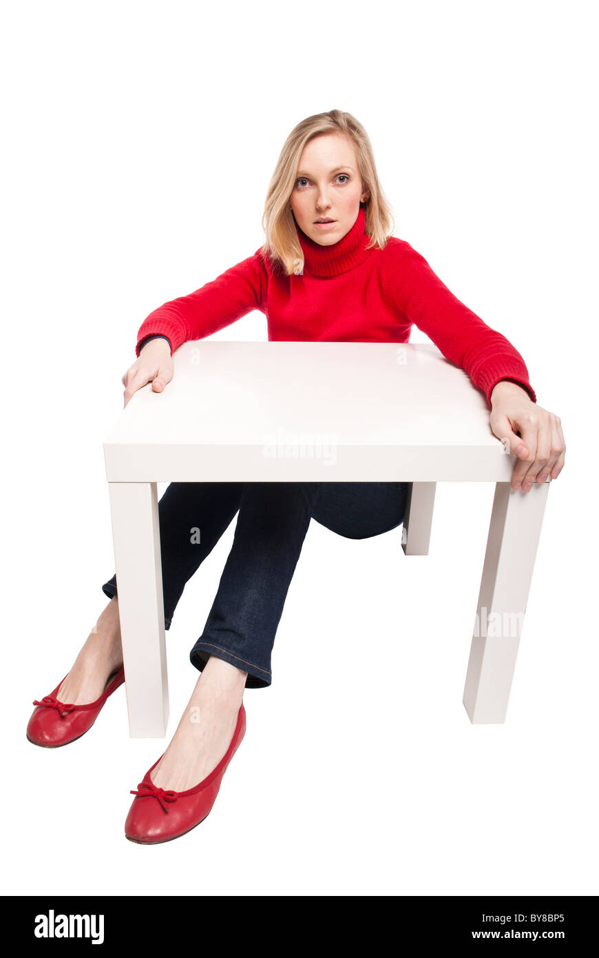 Young woman, office worker or student sitting at funny small desk ...