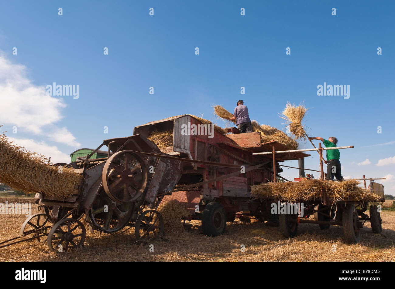 Two men working on a Ransomes threshing machine showing movement and ...