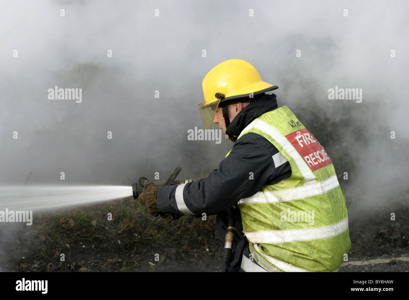 Fireman using a hose on a car fire Stock Photo - Alamy