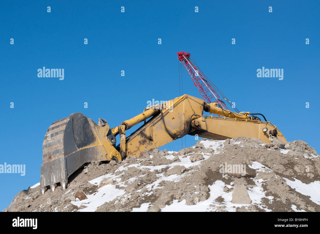 The arm and bucket of a hydraulic excavator on top of a pile of earth ...
