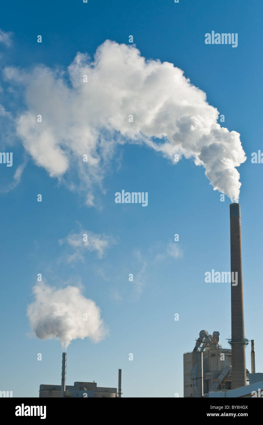 A manufacturing facility pumps smoke into the air from two smokestacks ...