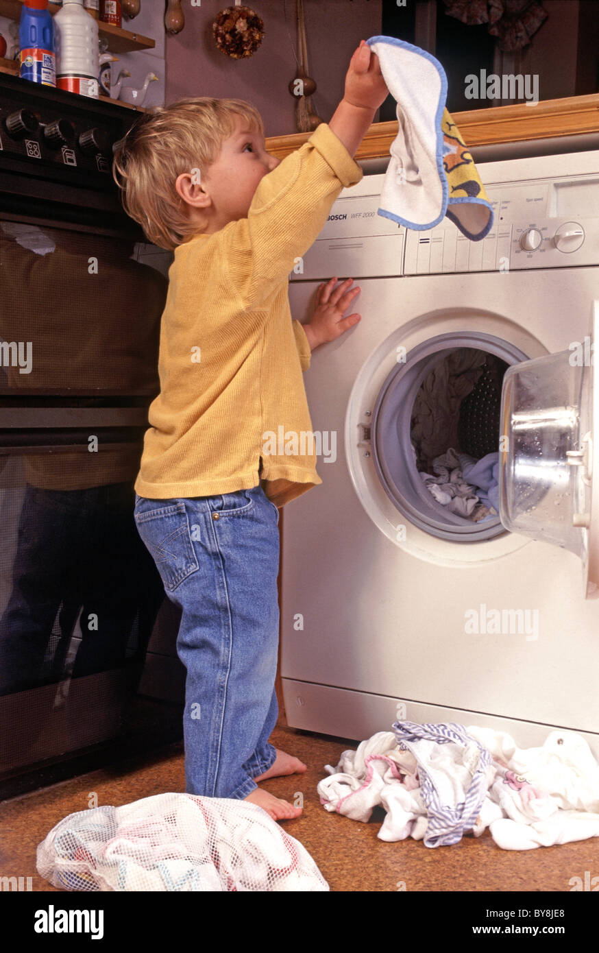 Toddler loading washing machine Stock Photo - Alamy