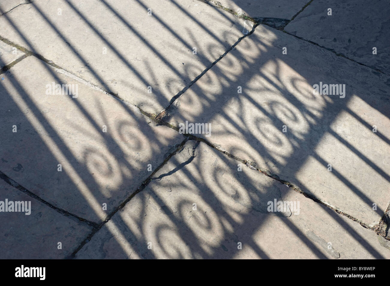 Shadow cast on the ground by a Victorian ornamental iron gate on a ...
