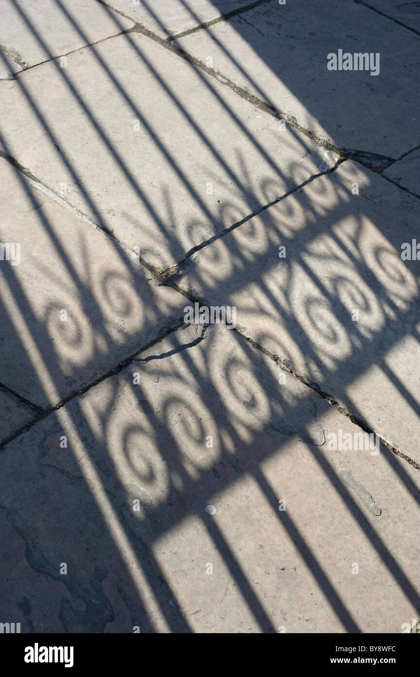 Shadow cast on the ground by a Victorian ornamental iron gate on a ...