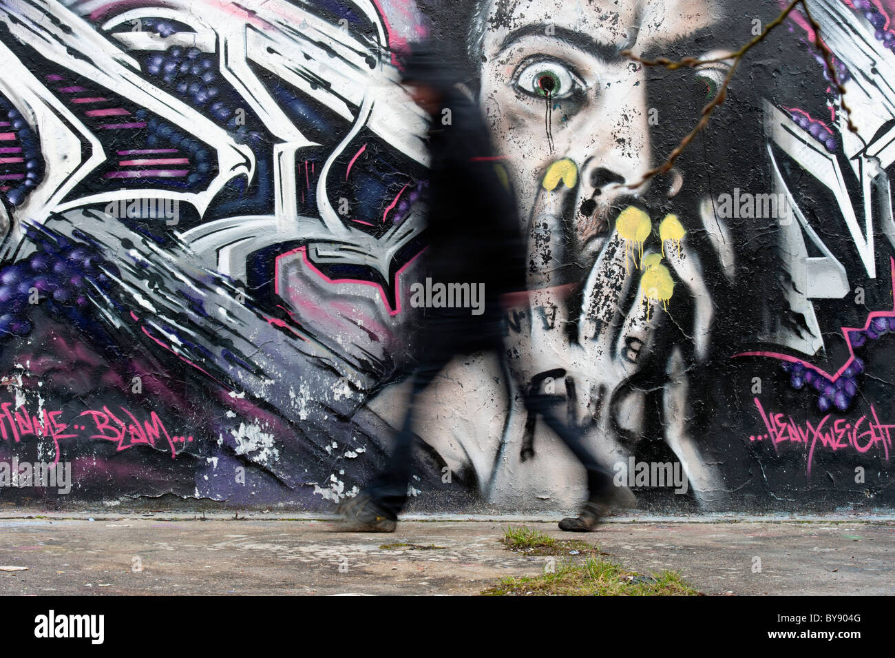 man walking past graffiti wall Stock Photo - Alamy