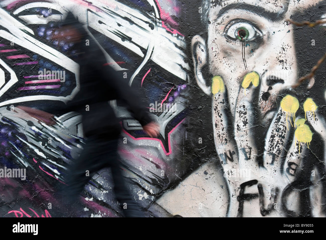 shadowy figure walking past graffiti wall Stock Photo - Alamy