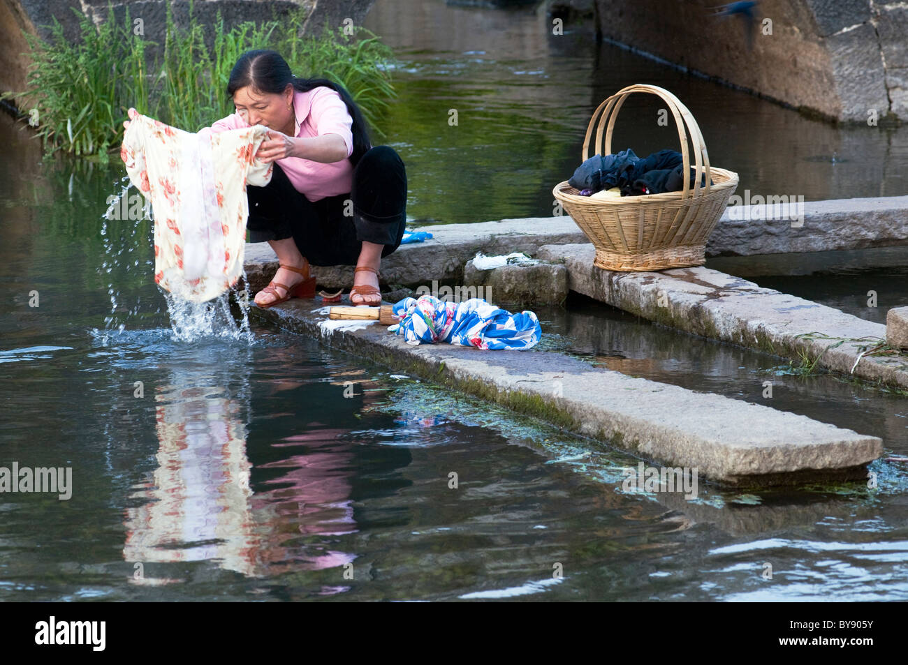 CHINA Woman washing clothes in the river in a village in Yunnan ...