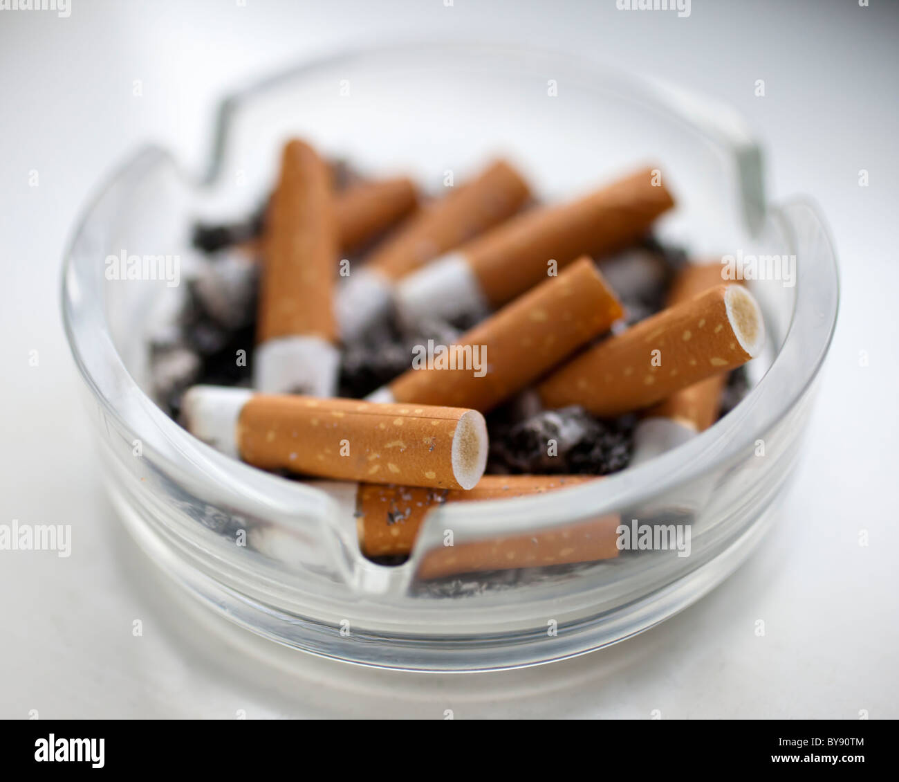 A dirty ashtray full of cigarette butts photographed with differential ...