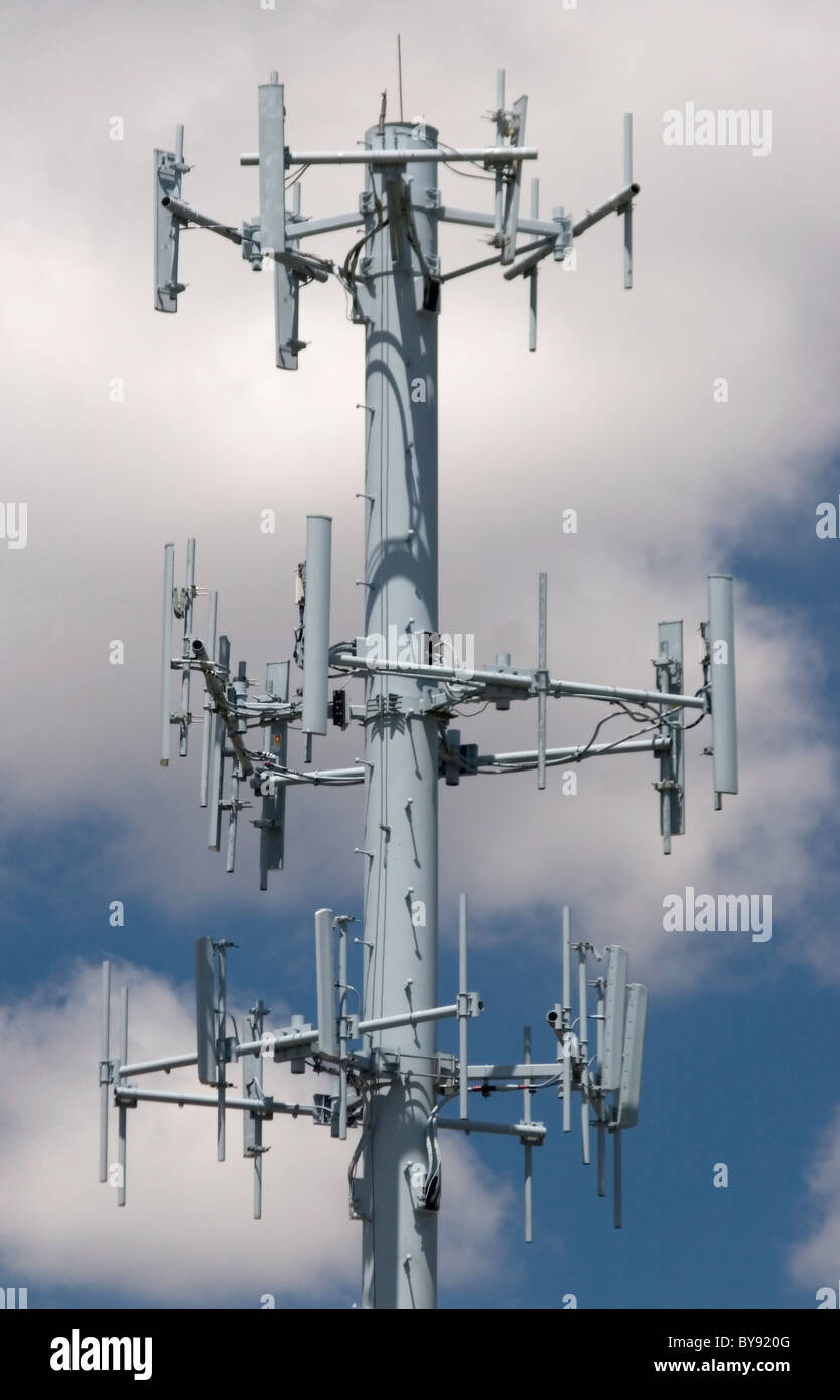 Cellular telecommunications tower against a cloudy blue sky Stock Photo ...
