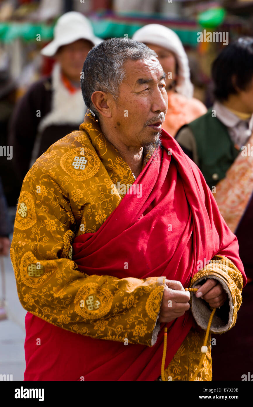Old Tibetan men pilgrim wearing a gold coat with red sash in the ...