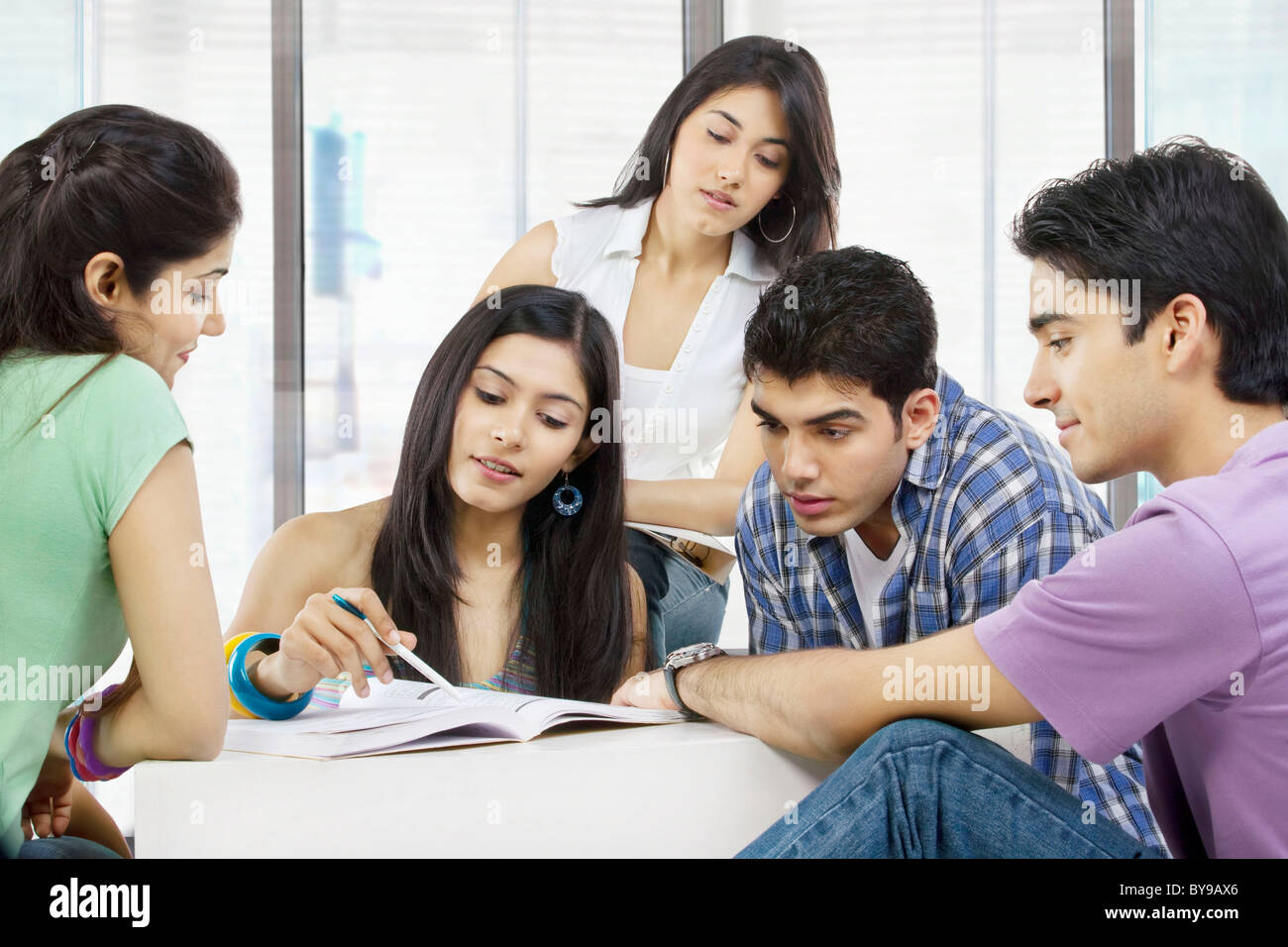 College students looking at a book Stock Photo - Alamy