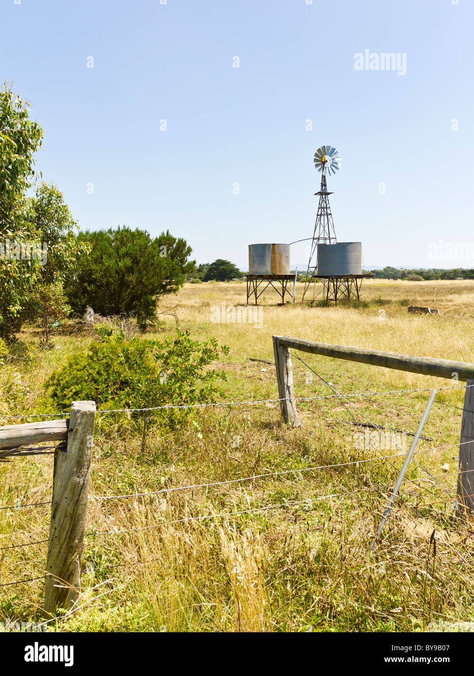 Barbed wire fences and bore water windmill in background, in australian ...