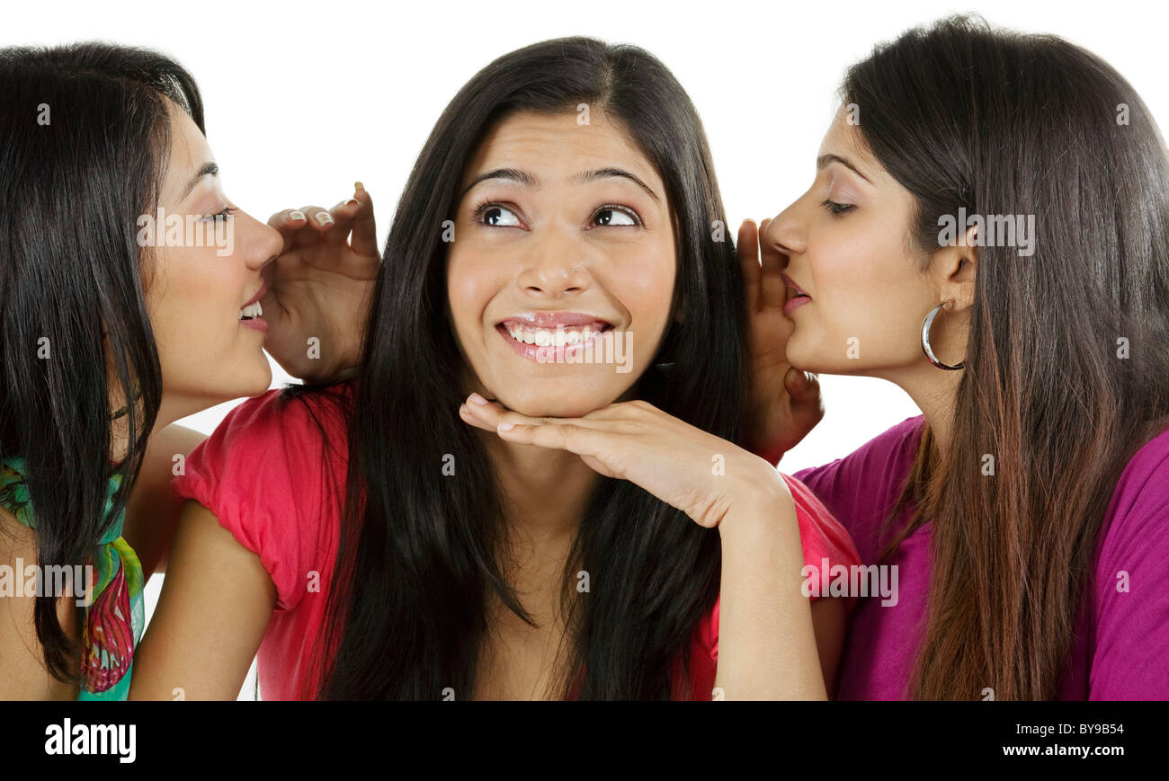 Girls whispering into their friends ear Stock Photo - Alamy