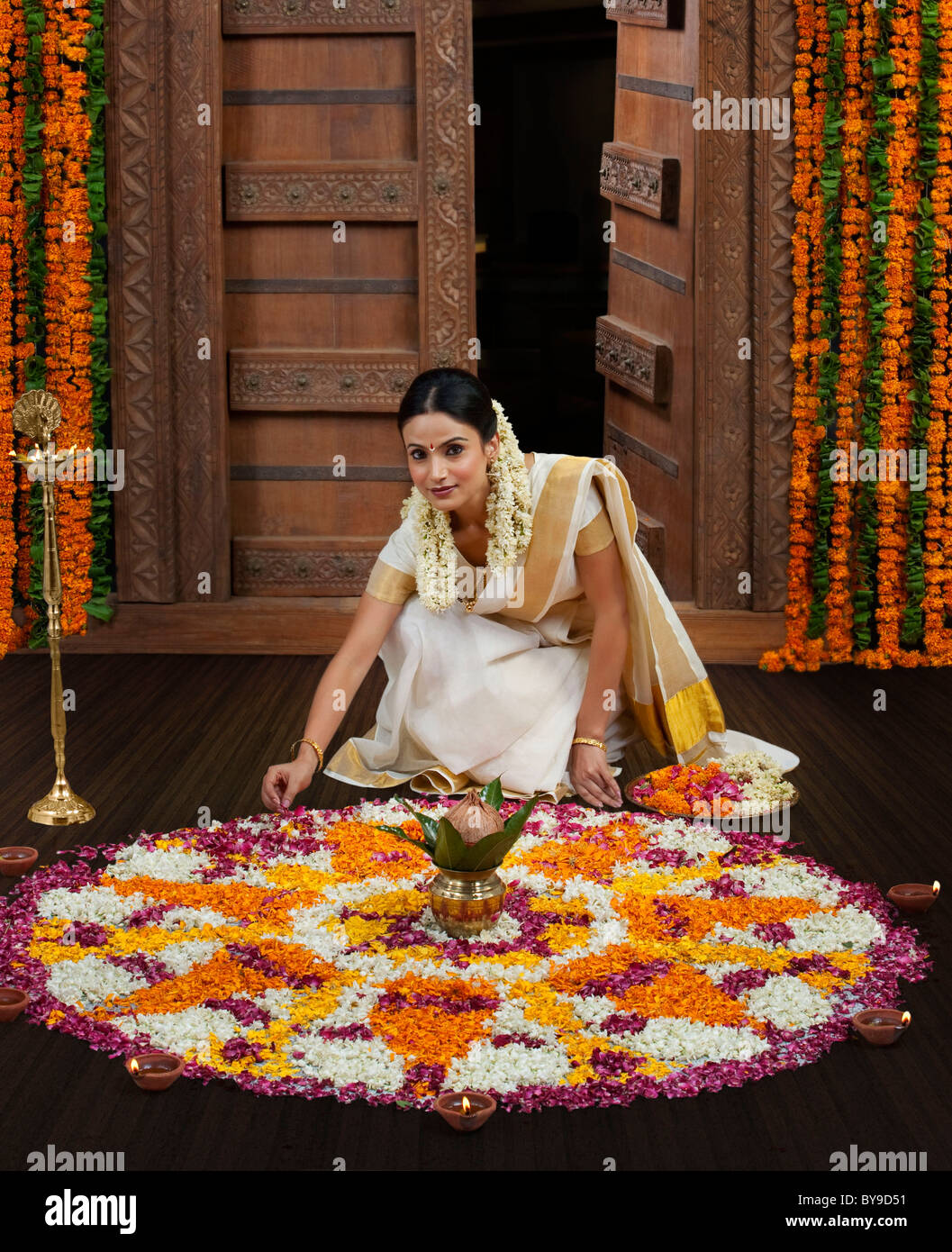 South Indian woman making a flower rangoli Stock Photo - Alamy
