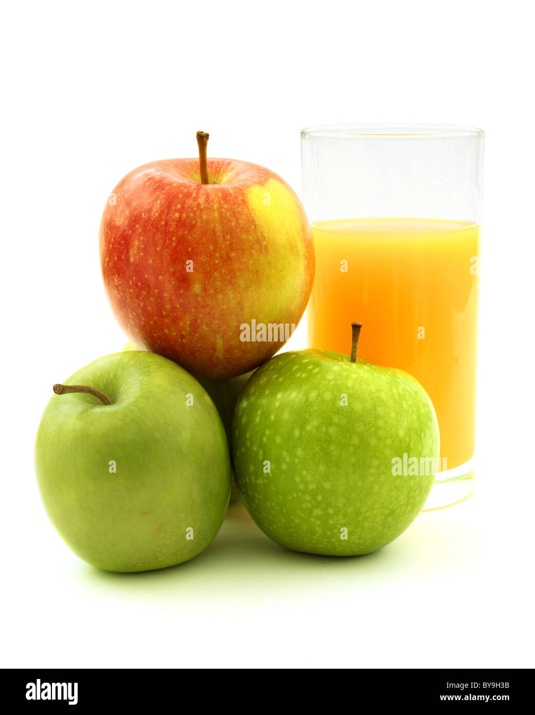 A stack of apples and a glass of orange juice on a white background ...