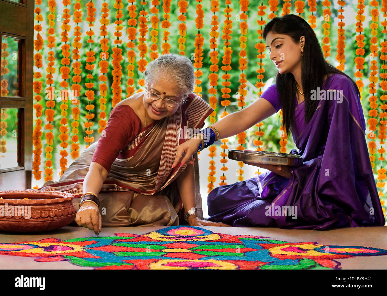 Mother and daughter making a rangoli Stock Photo - Alamy