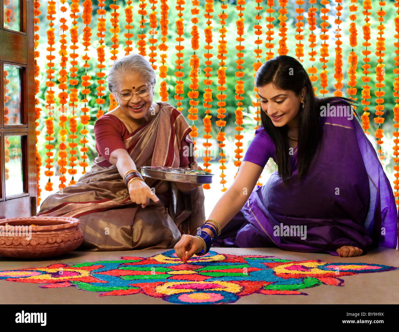 Mother and daughter making a rangoli Stock Photo - Alamy