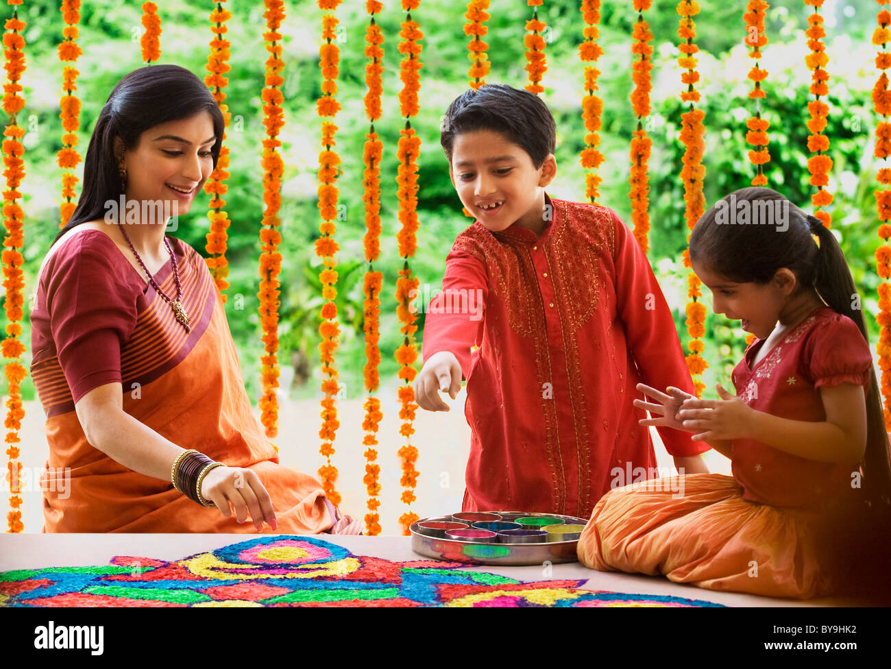 Woman making a rangoli while her children watch Stock Photo - Alamy