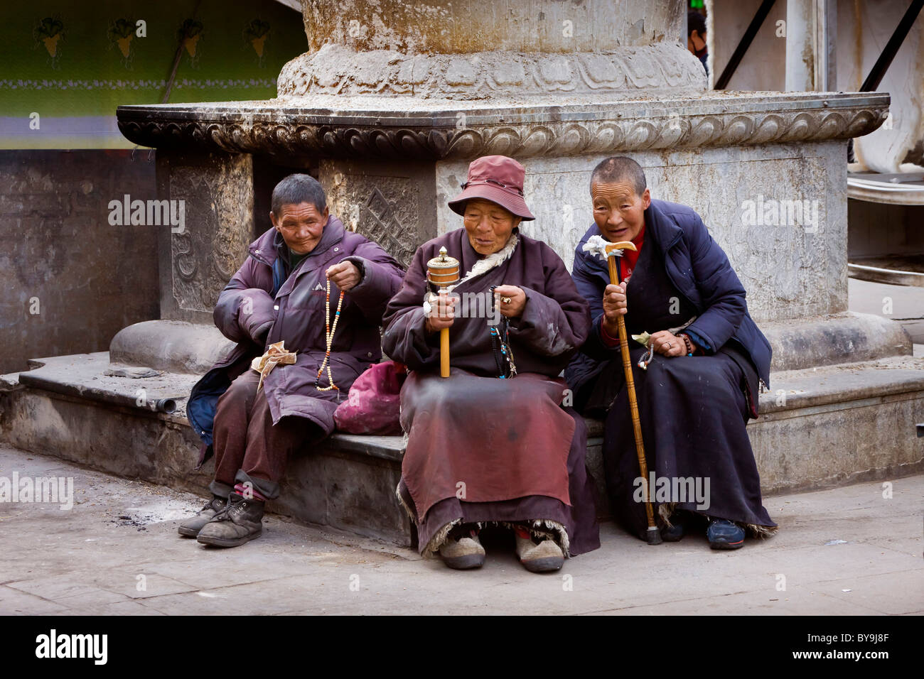 Three old Tibetan pilgrim women with prayer wheel and beads in the ...
