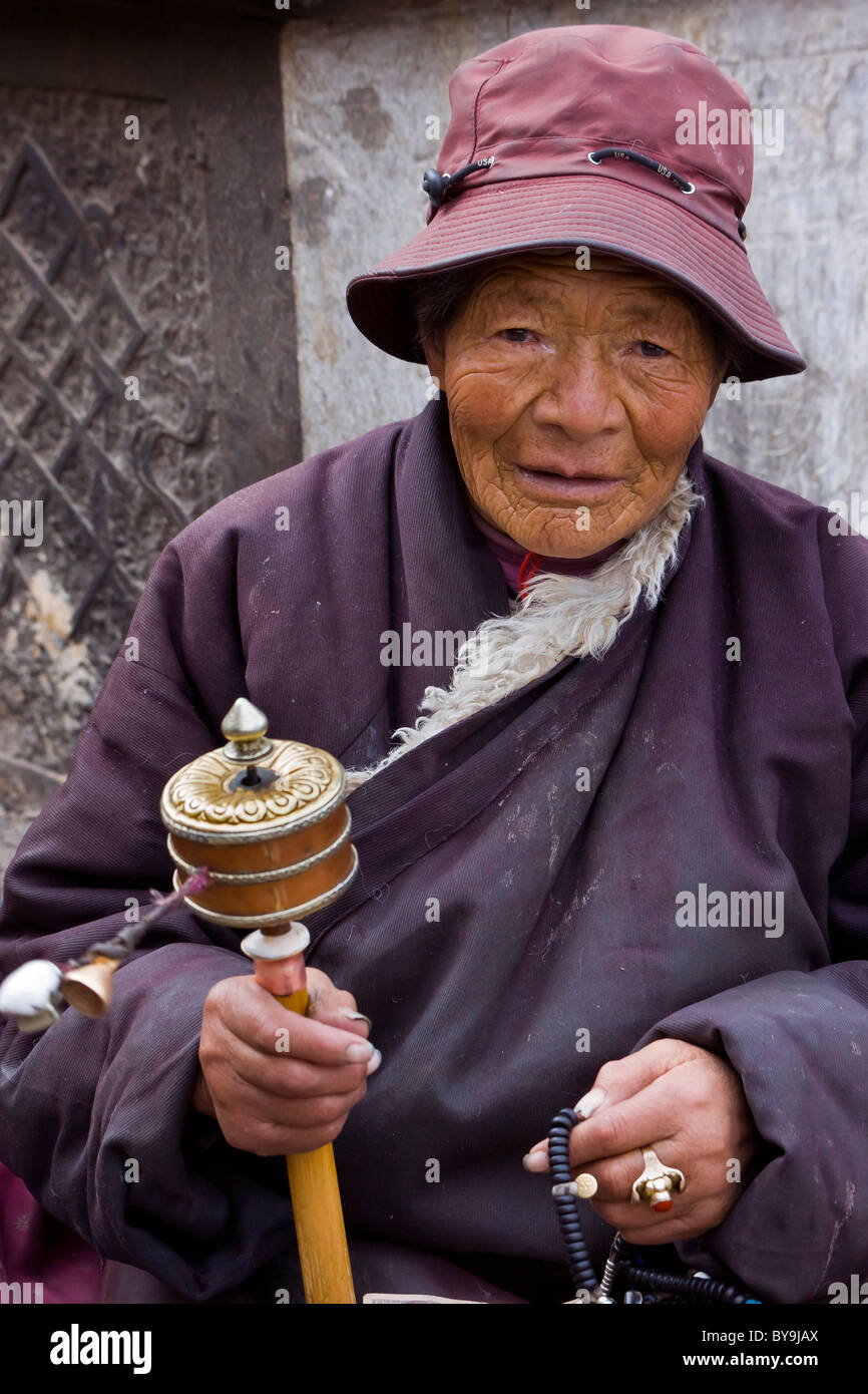 Old Tibetan pilgrim woman with prayer wheel and beads in the Barkhor ...