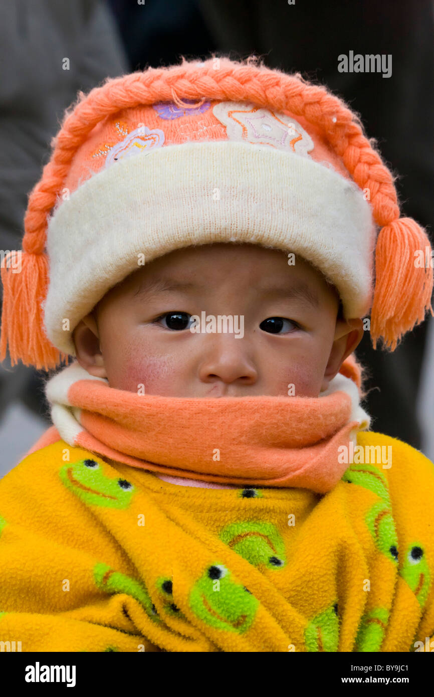 Young Tibetan child in yellow jacket and orange and white knitted cap ...