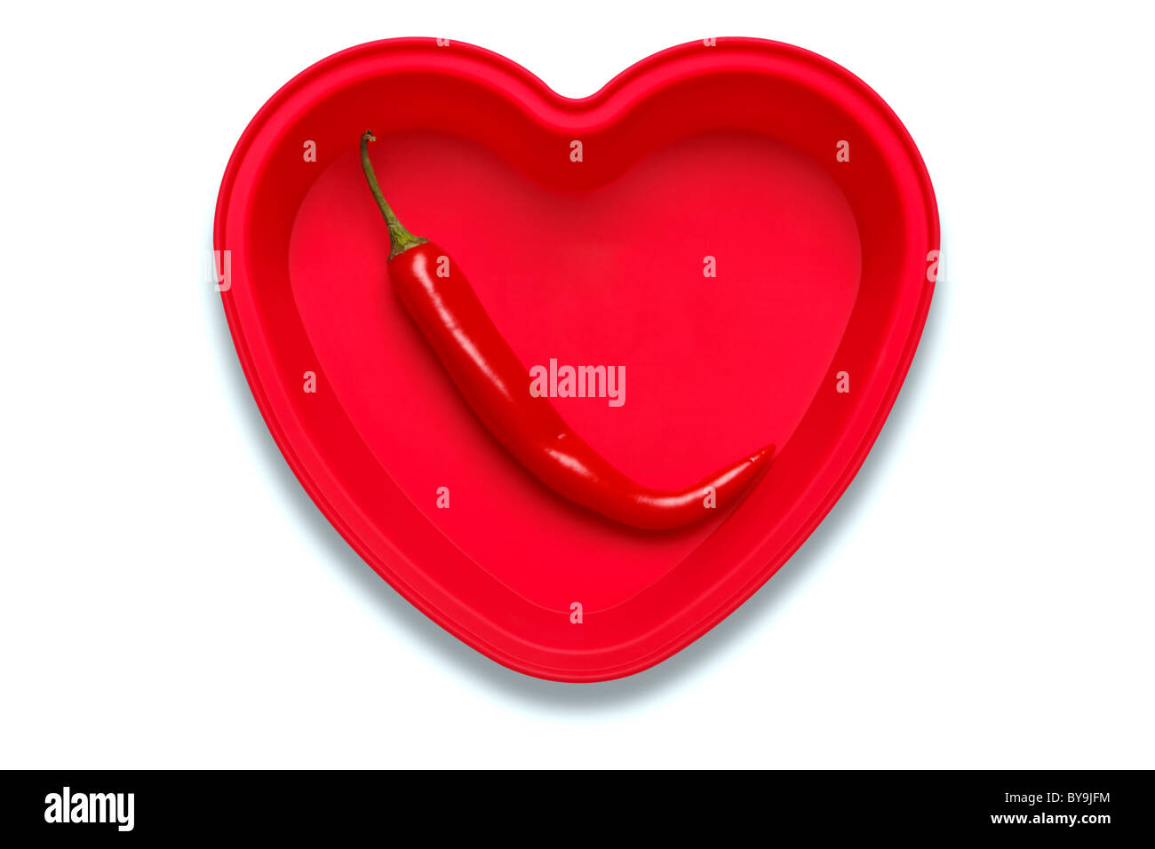 Conceptual photo of a chilli pepper in a heart shaped dish to represent ...