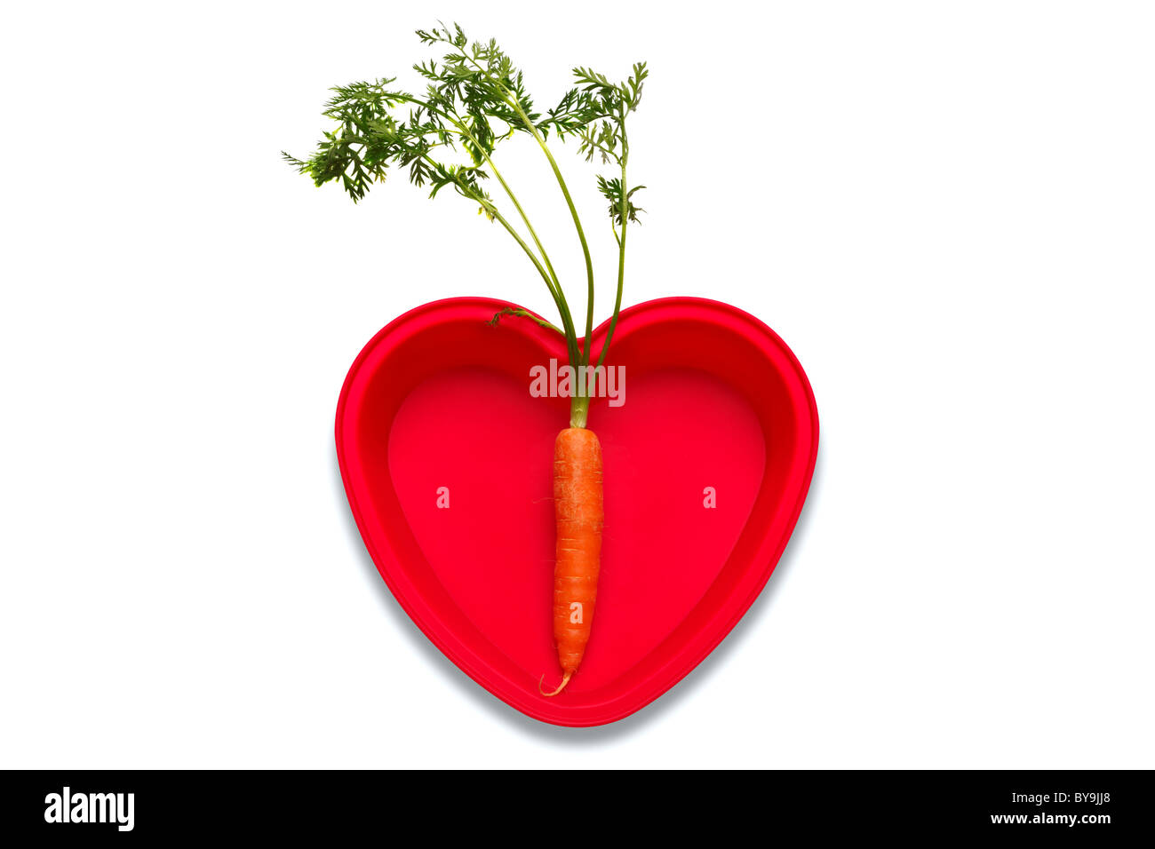 Conceptual photo of a carrot in a heart shaped dish to represent a love ...