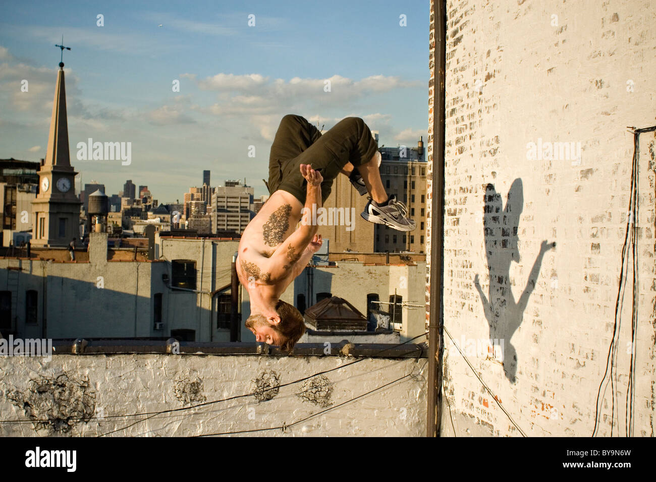 Traceur flipping off of a wall with New York City in the background ...