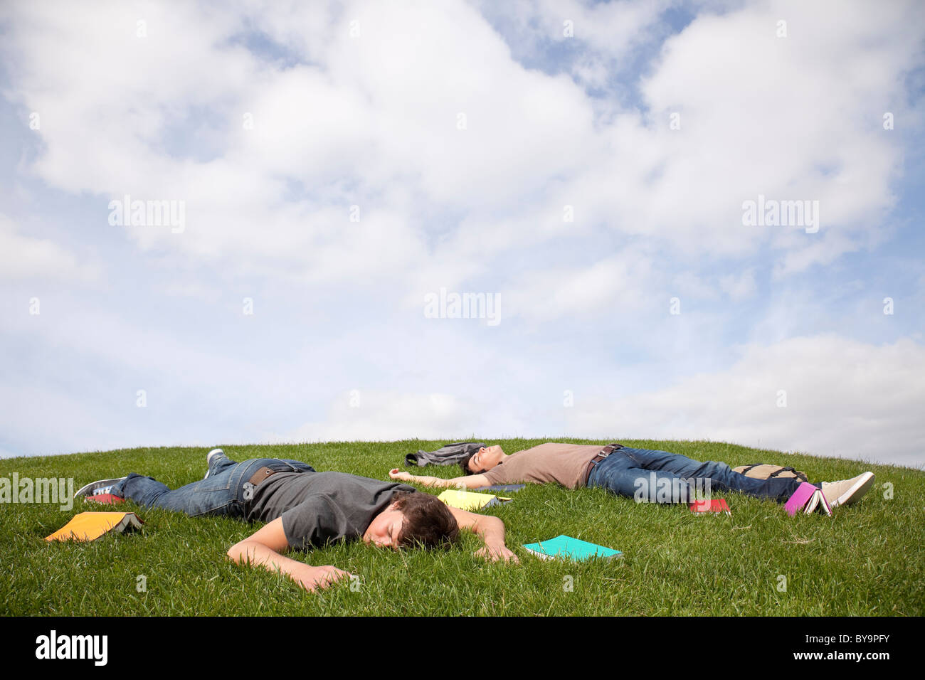 two young student lying down at the school grass after long hours of ...