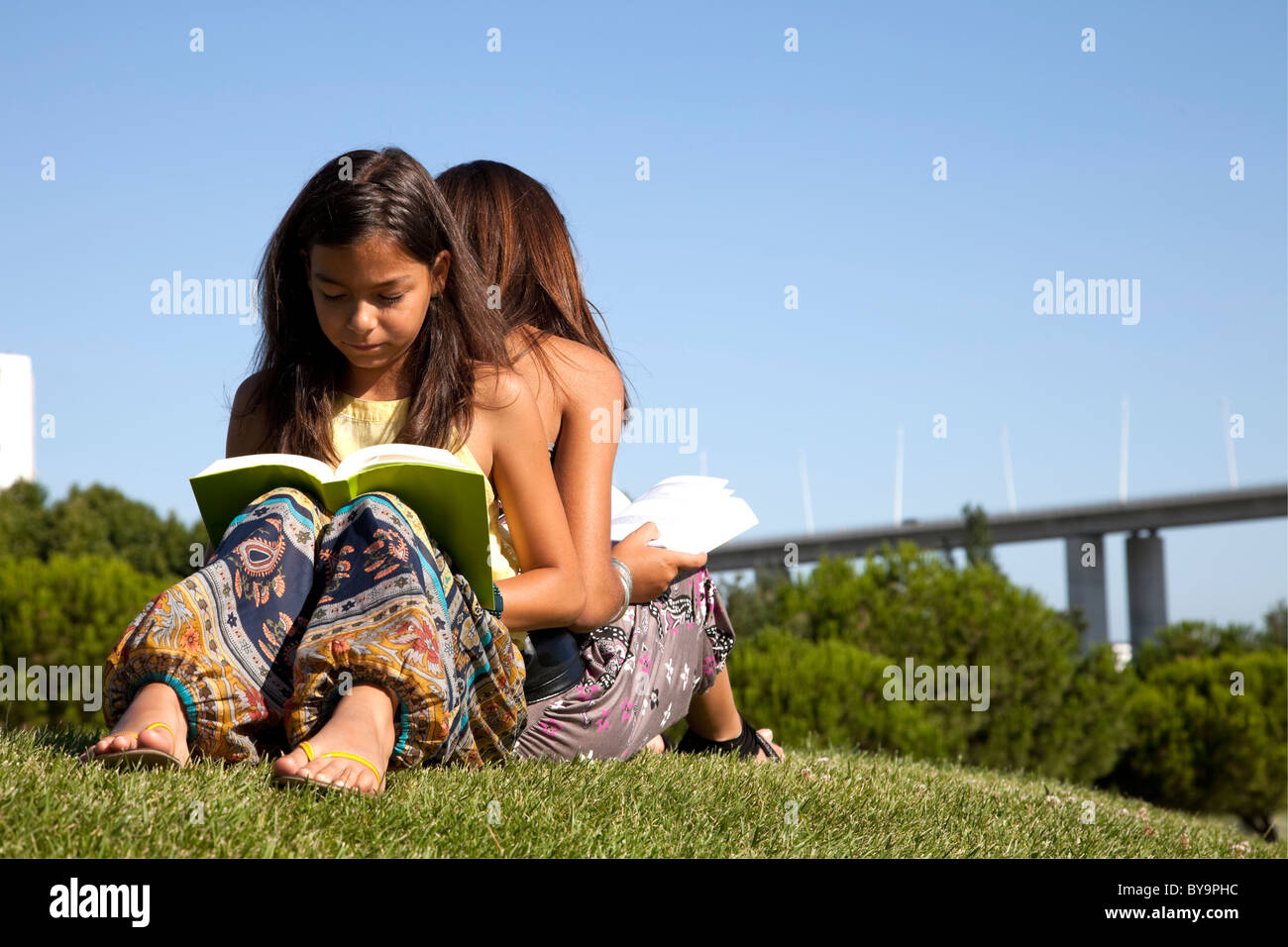 two young sisters reading books at the park Stock Photo - Alamy