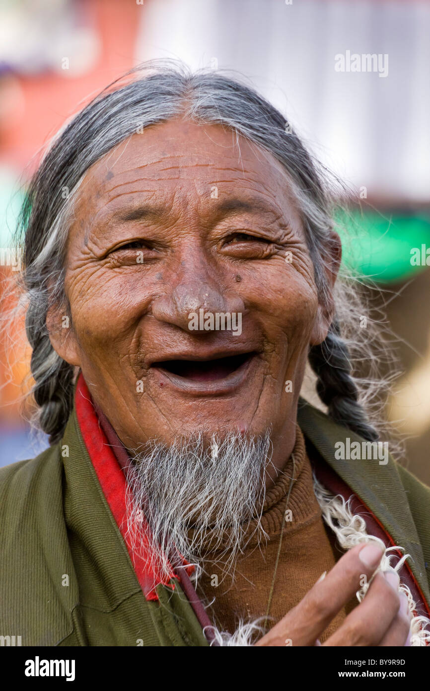 Smiling Tibetan old man pilgrim with pigtails and grey beard in the ...