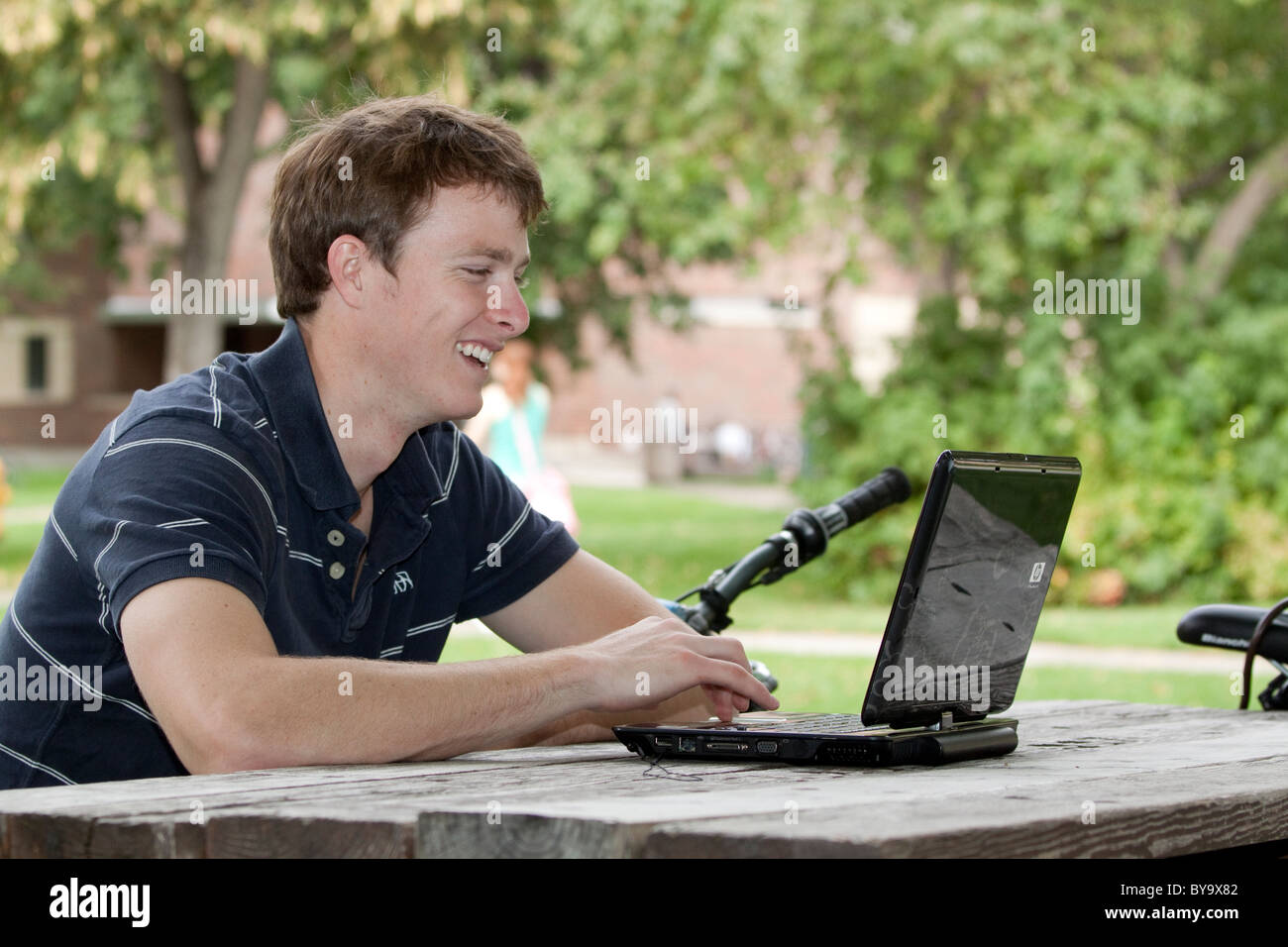 Young man laughing over something he is reading on his laptop computer ...