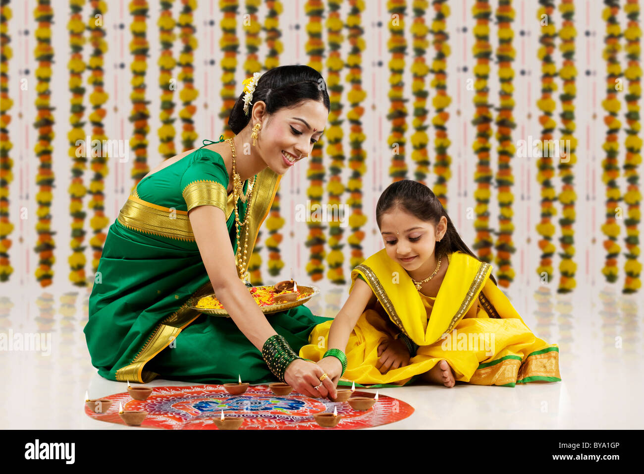 Mother and daughter placing diyas on a rangoli Stock Photo - Alamy