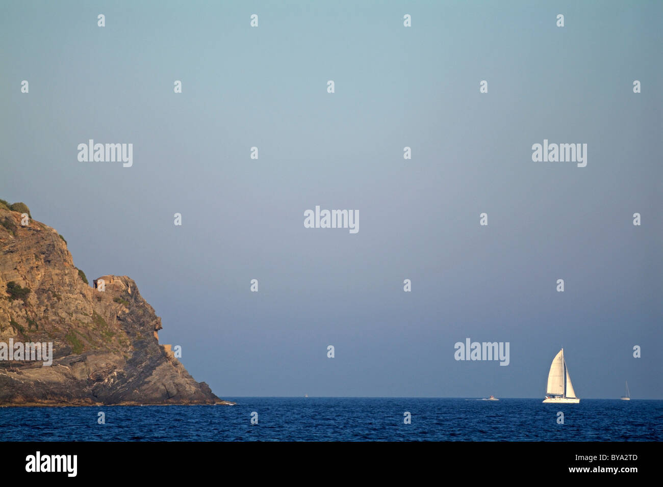 Rocky cliffs and sailboat navigating the waters of the Mediterranean ...
