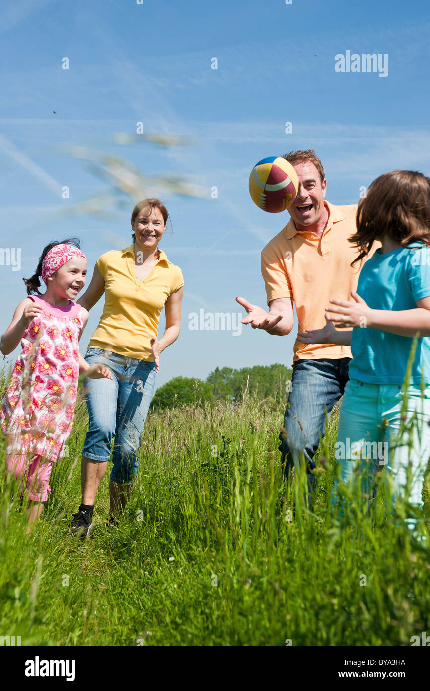 Family playing joyfully with a ball in a flower meadow Stock Photo - Alamy