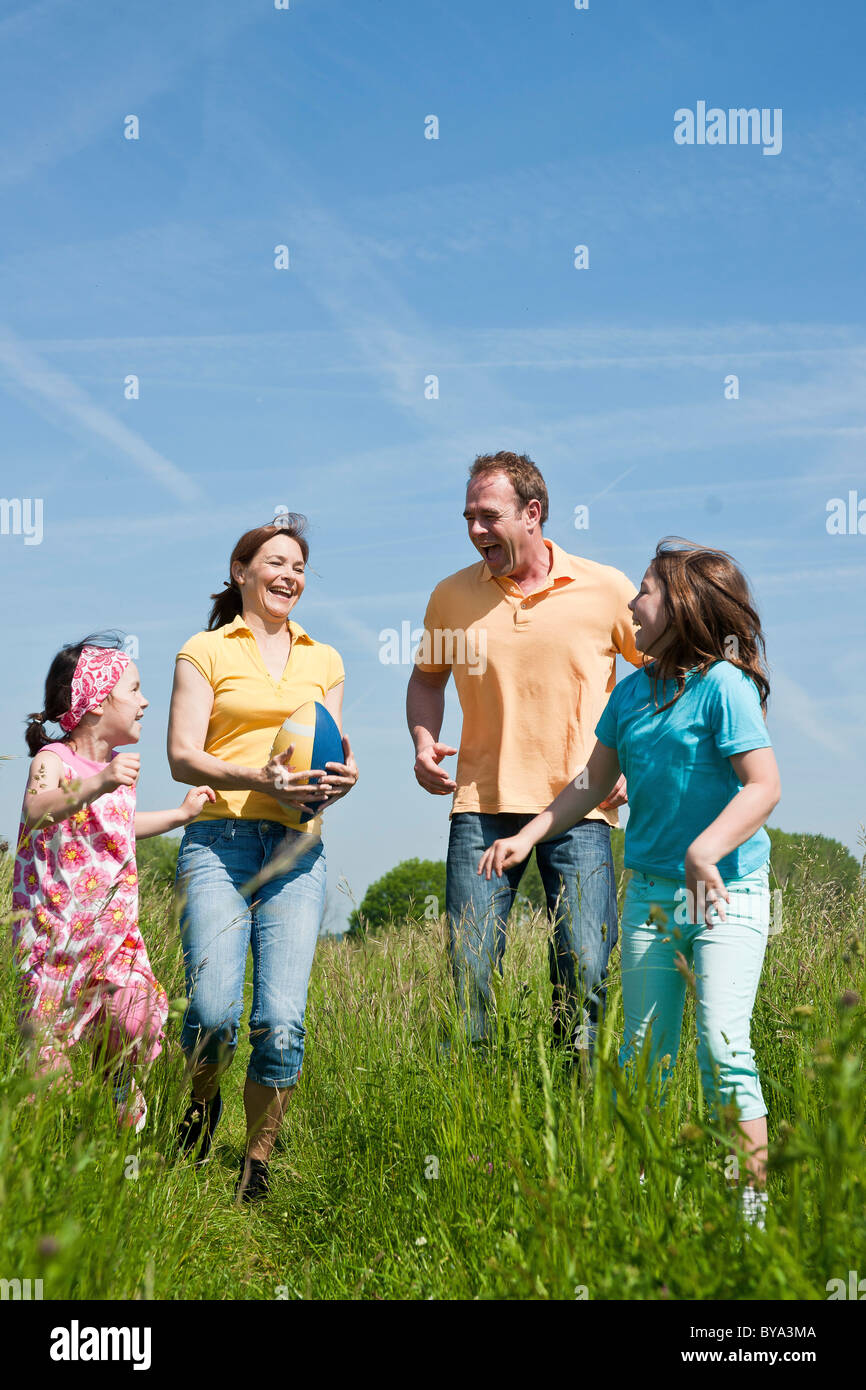 Family playing joyfully with a ball in a flower meadow Stock Photo - Alamy
