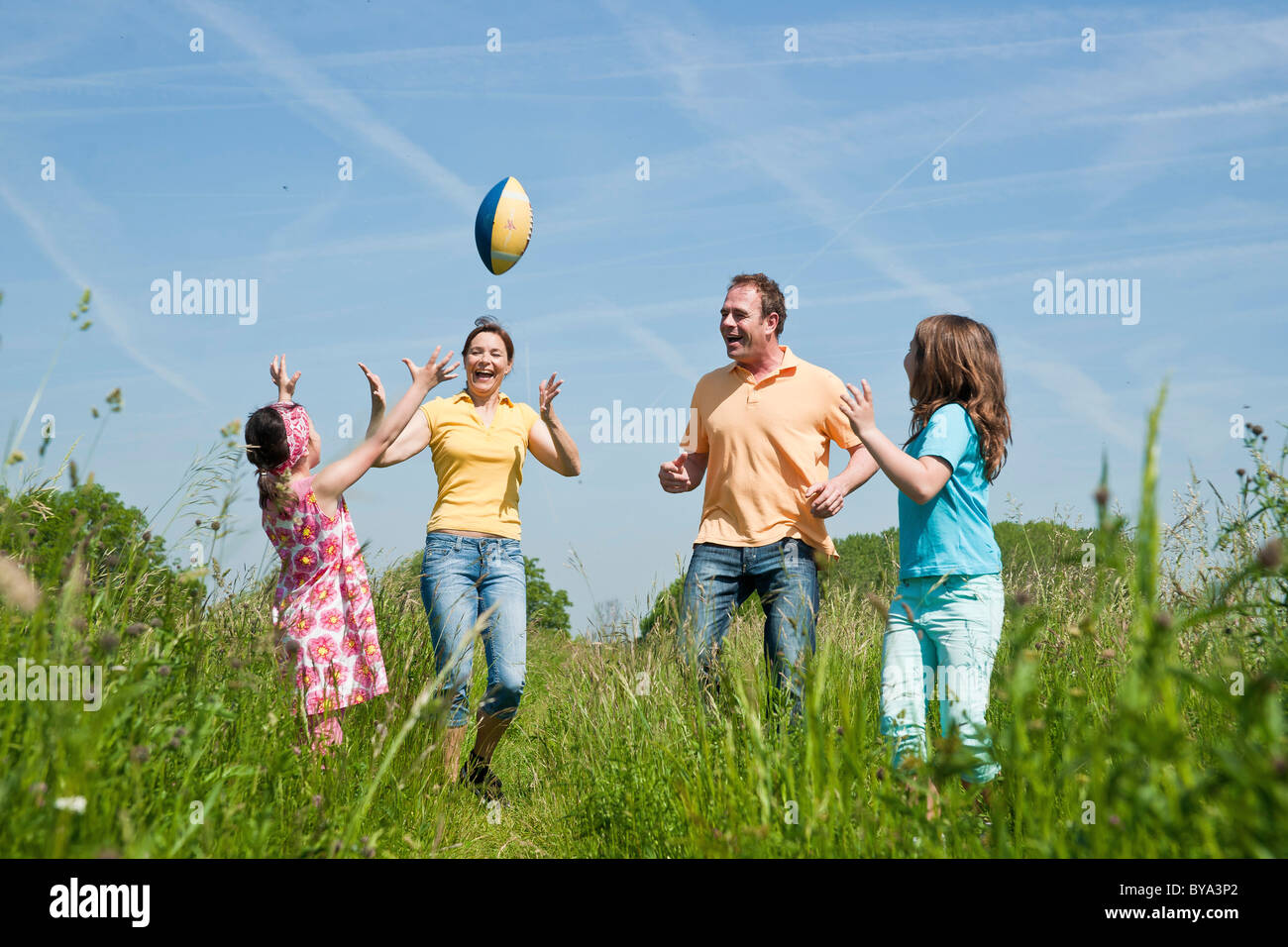 Family playing joyfully with a ball in a flower meadow Stock Photo - Alamy