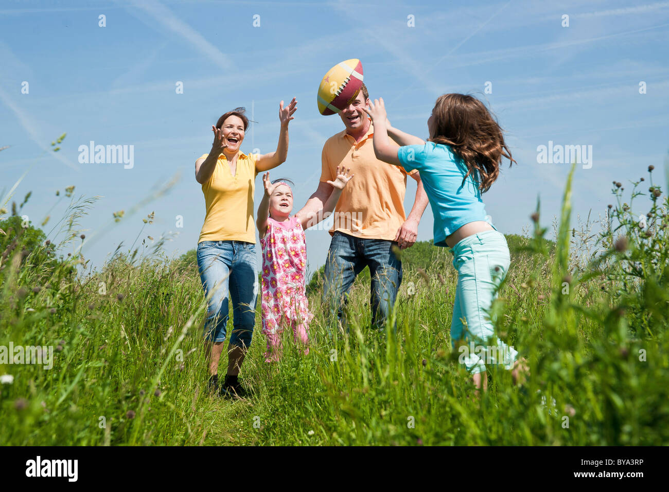 Family playing joyfully with a ball in a flower meadow Stock Photo - Alamy