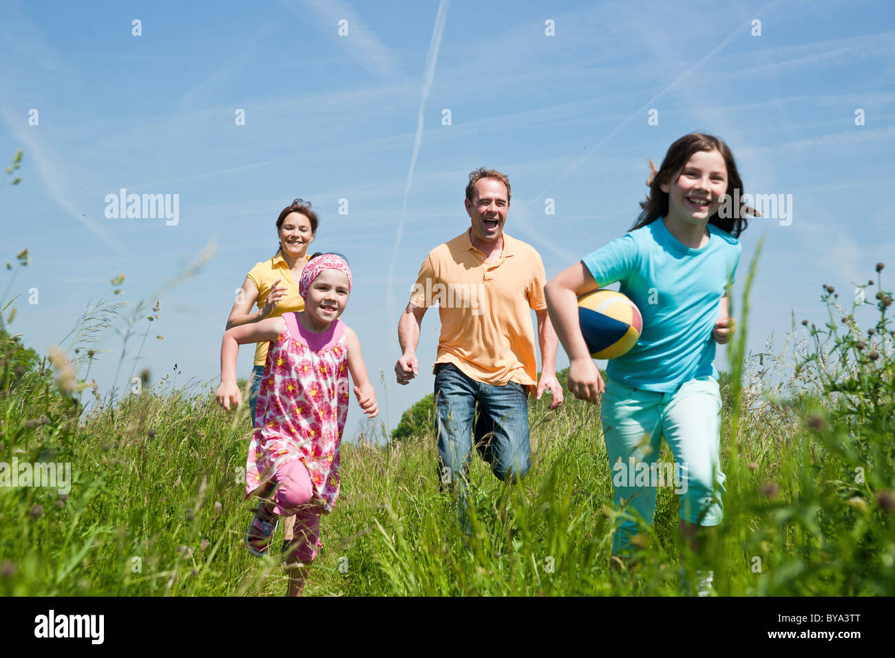 Family playing joyfully with a ball in a flower meadow Stock Photo - Alamy