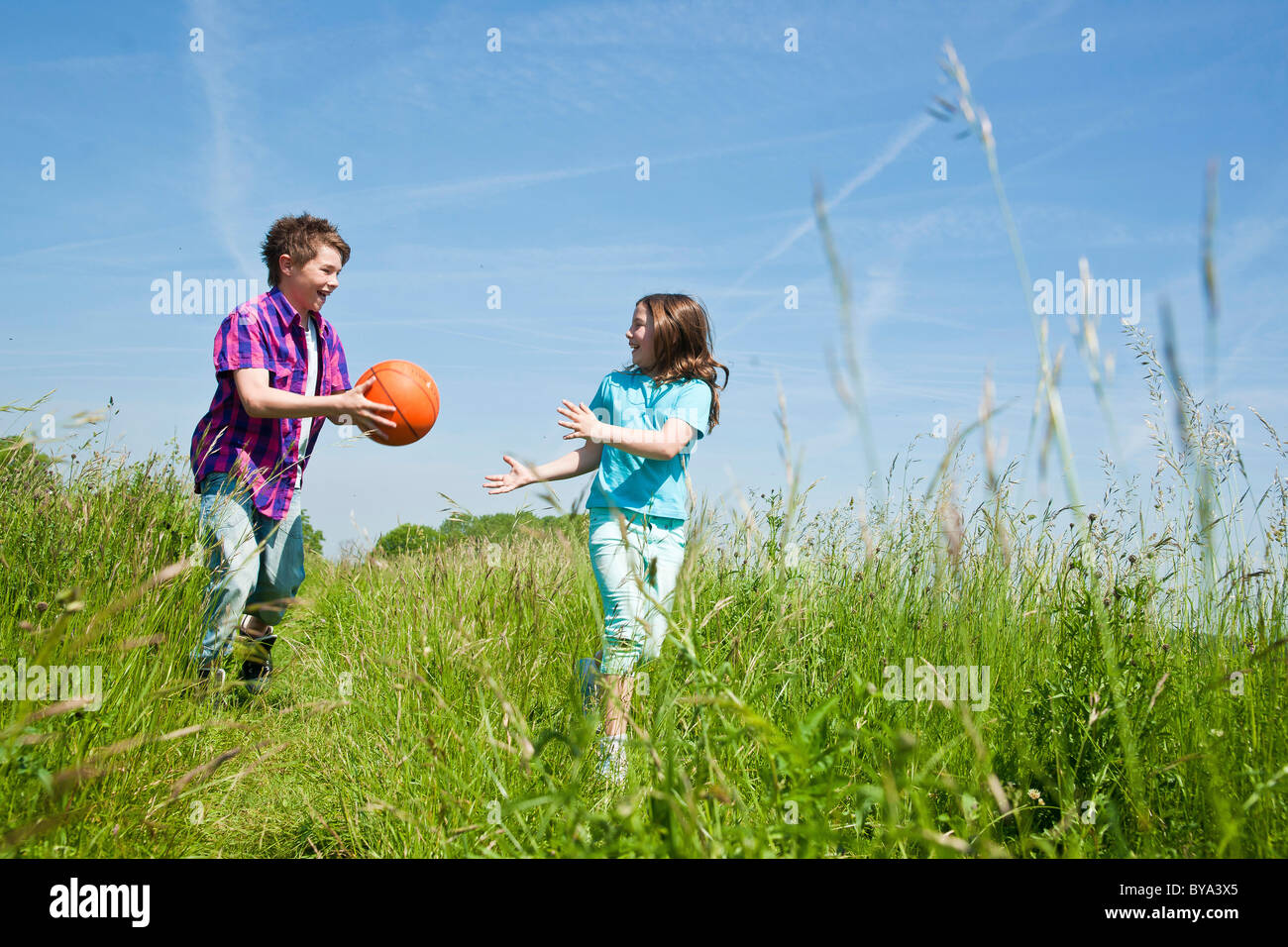 Children running across a field with a ball Stock Photo - Alamy